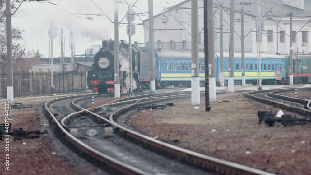 Steam locomotive train approaching station passing through a goods yard ...