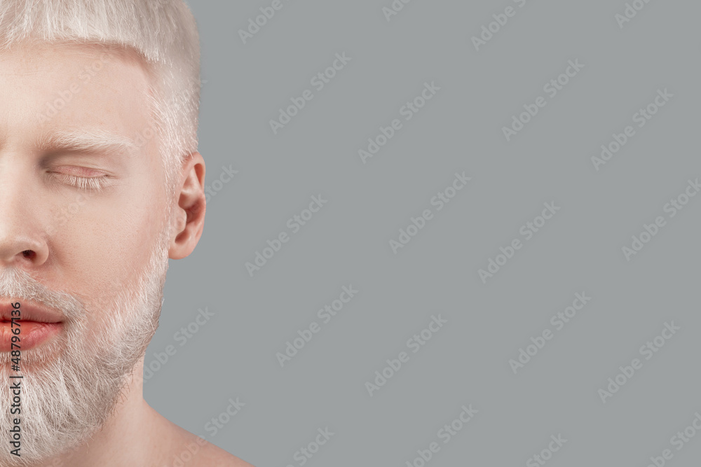 Half face portrait of young albino man with closed eyes, pale skin and ...
