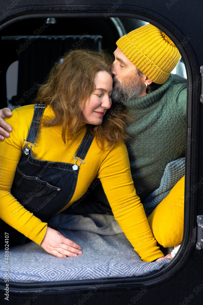 Loving mature couple in mini camper traveling. Man kiss woman on ...