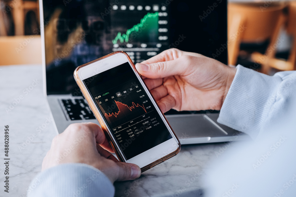 Stock market investor hands holding a phone investment app index growth ...