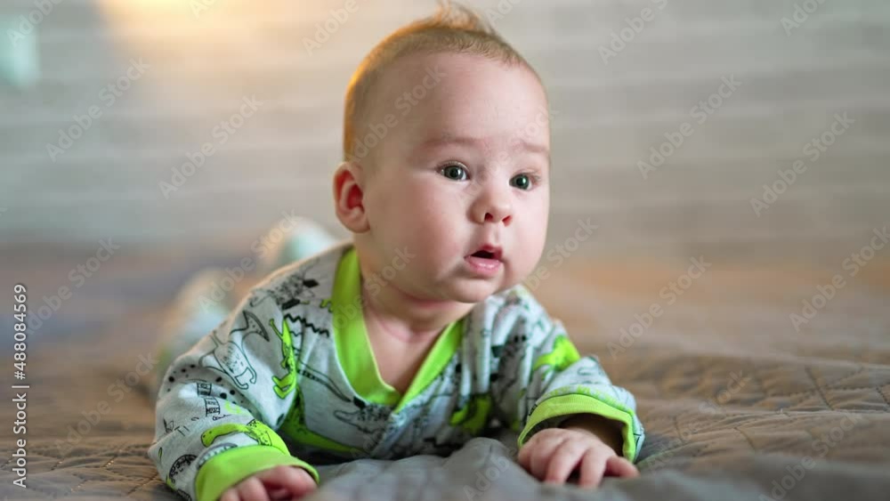 Nice sweet baby boy with plump cheeks lies on his stomach. Portrait of ...