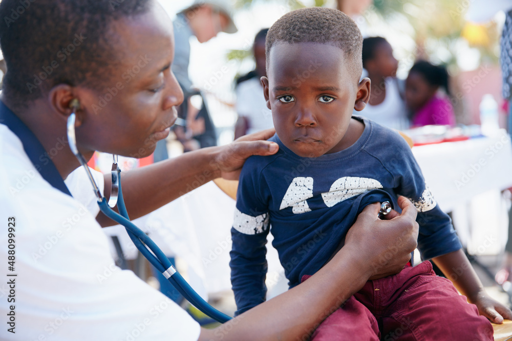 Keeping kids healthy. Shot of a volunteer doctor giving checkups to ...