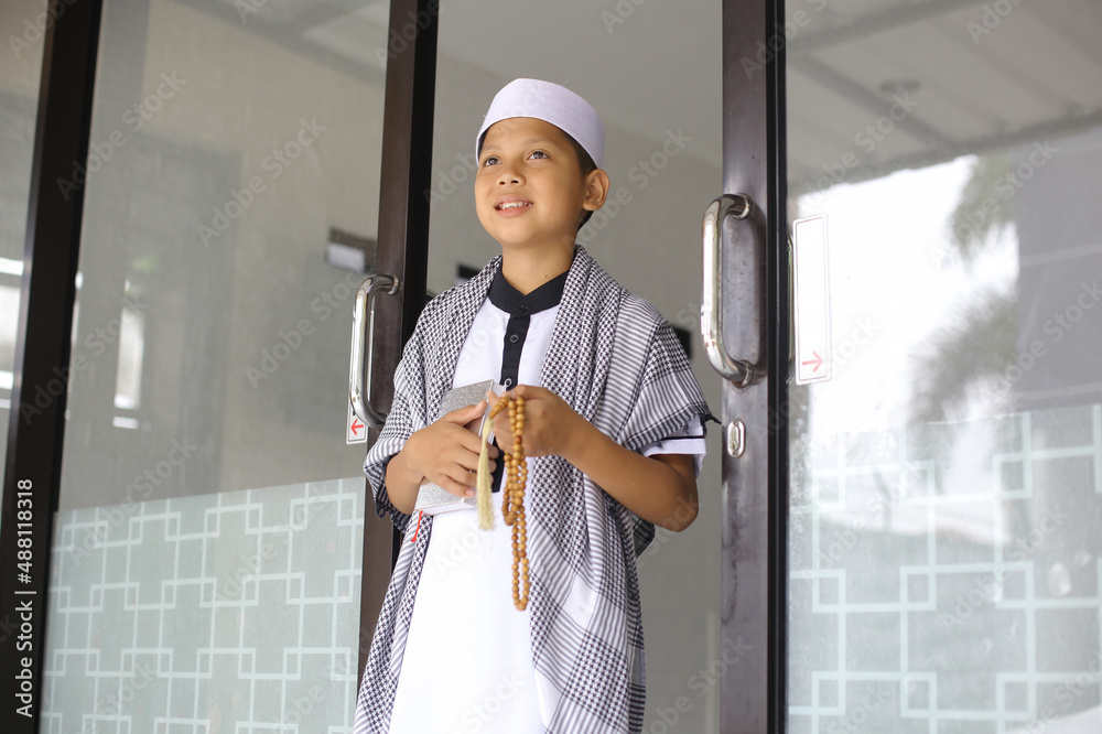 Smiling muslim boy holding al quran and tasbih and walking out from ...