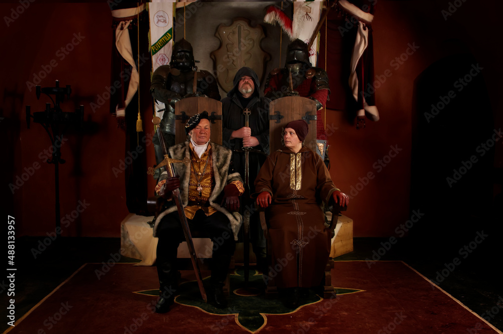 An elderly medieval count (baron, prince) sits on a throne with sword ...