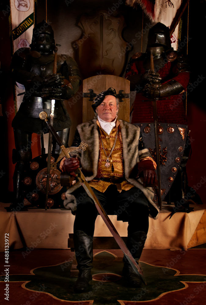 Medieval elderly count (baron, prince) sits on a throne with sword in ...