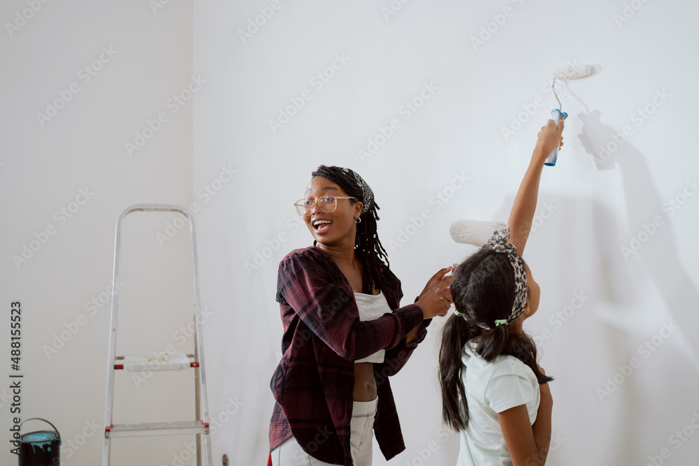 Mom spends time with her daughter, together they painting walls in a ...
