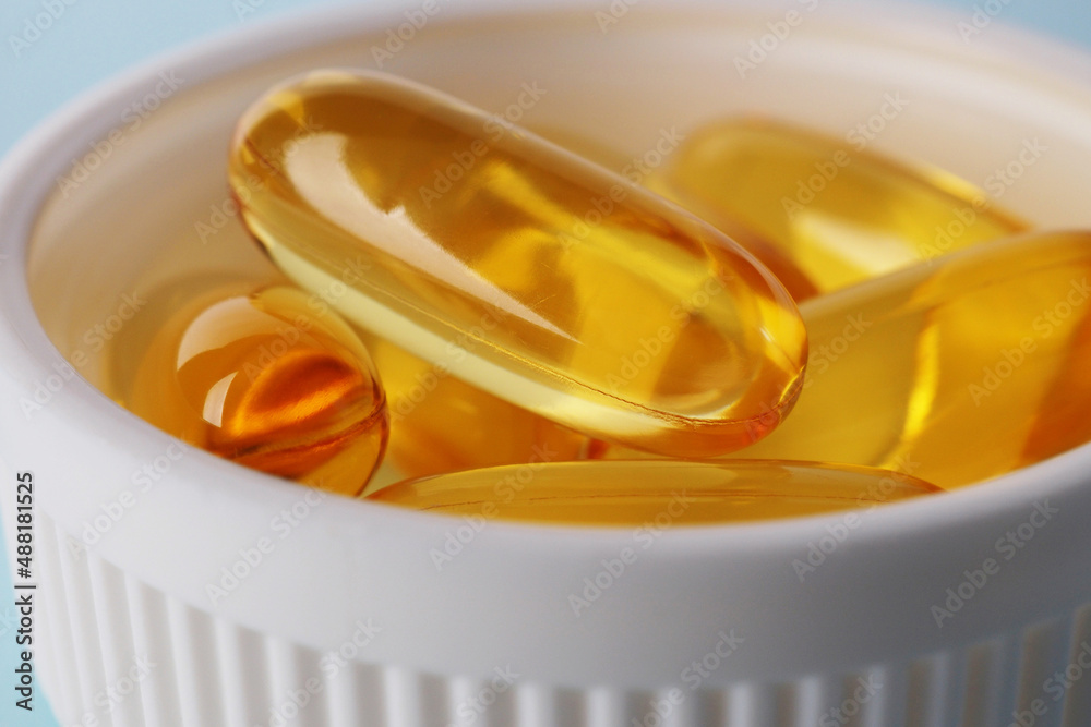 Fish oil. Yellow softgels or capsules are in white bottle cap. Light ...