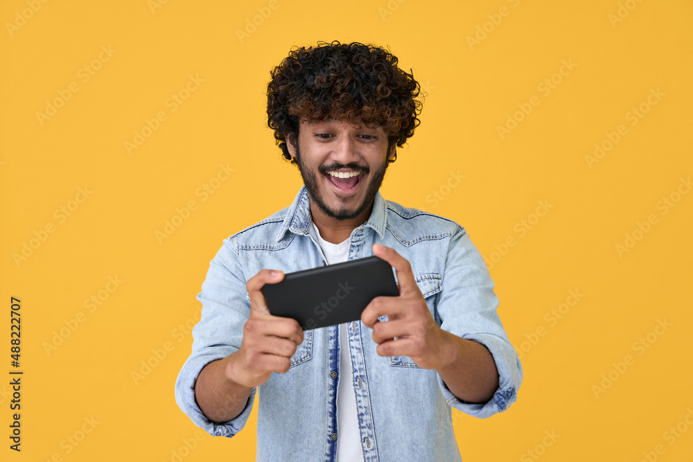 Excited happy young indian man gamer player using smartphone playing ...