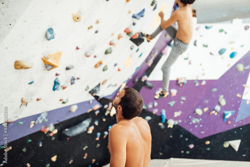 Handsome athletic men climbing on a indoor climbing wall. Extreme ...