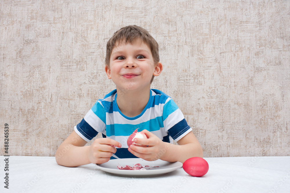 child with happy face peeling an Easter egg. Close-up portrait of cute ...