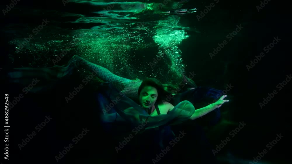 two mysterious sirens are floating in dark depth of magical sea or lake ...