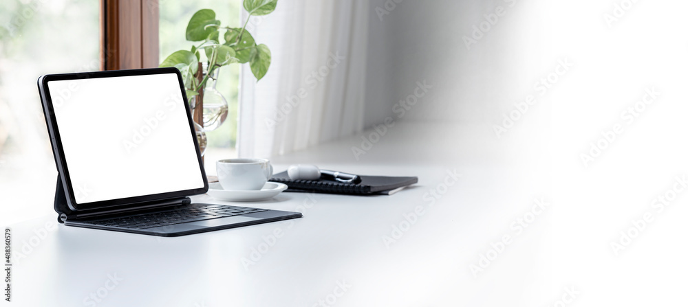 Blank white screen tablet with magic keyboard in modern office room ...