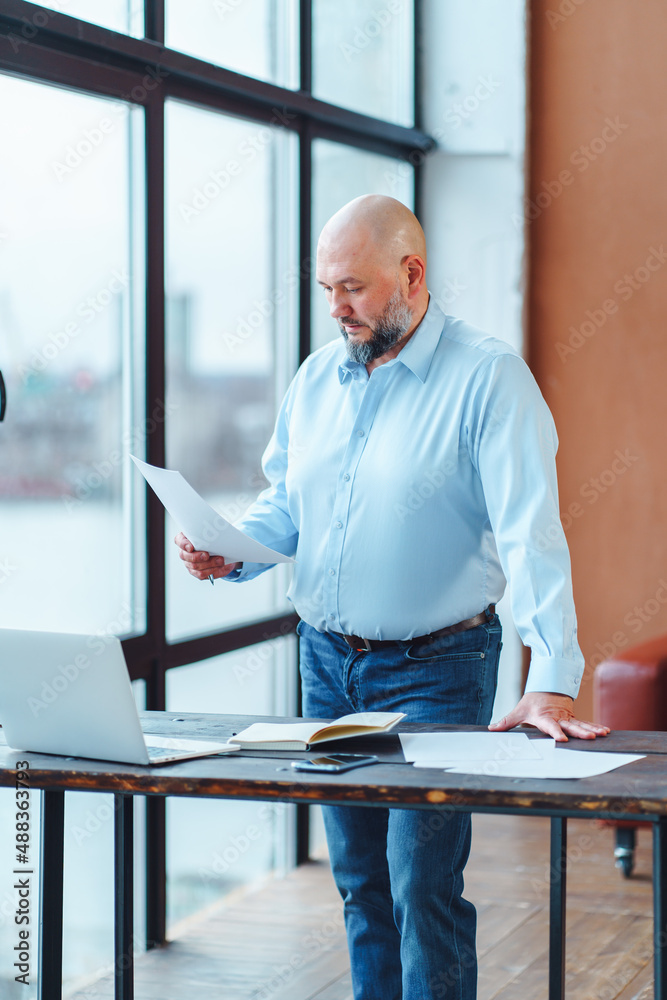 Vertical portrait of confident bald adult man with beard staying near ...