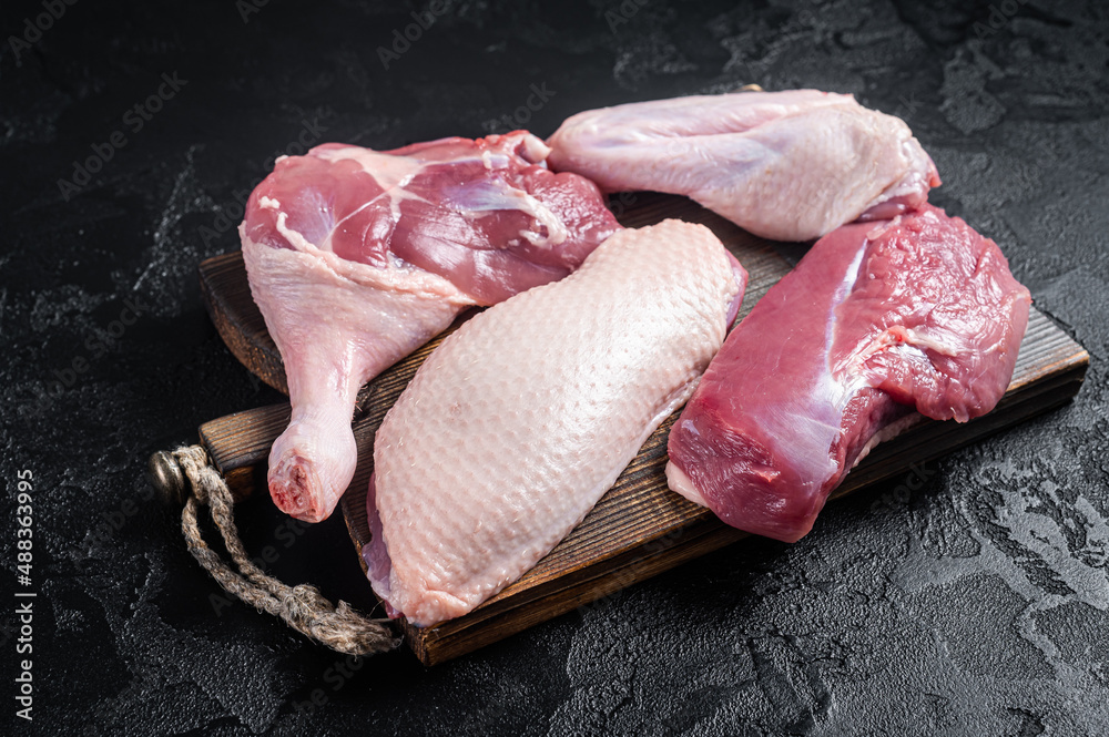 Duck breast fillet, legs, wings, raw meat on a butcher cutting board ...