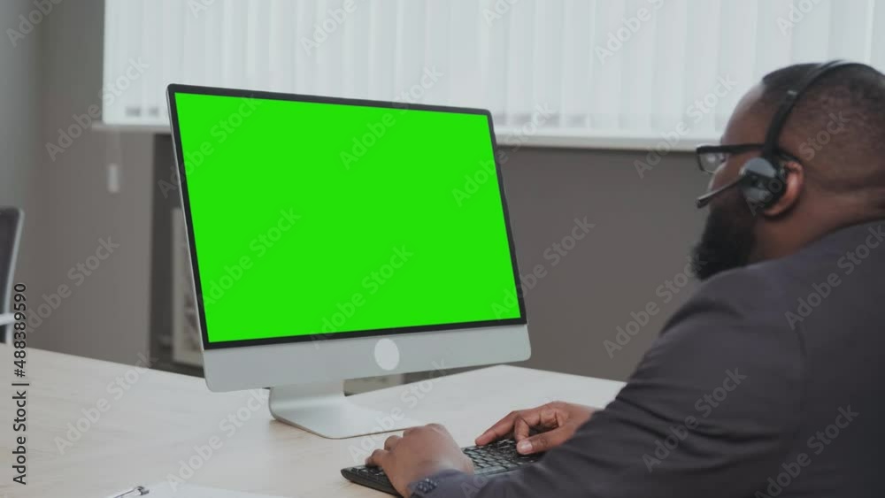 African american man working with horizontal green screen on computer ...