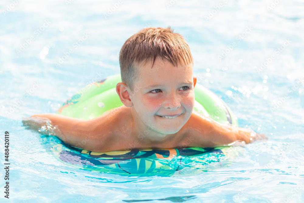 Funny happy child boy in swiming pool on inflatable rubber circle ring ...