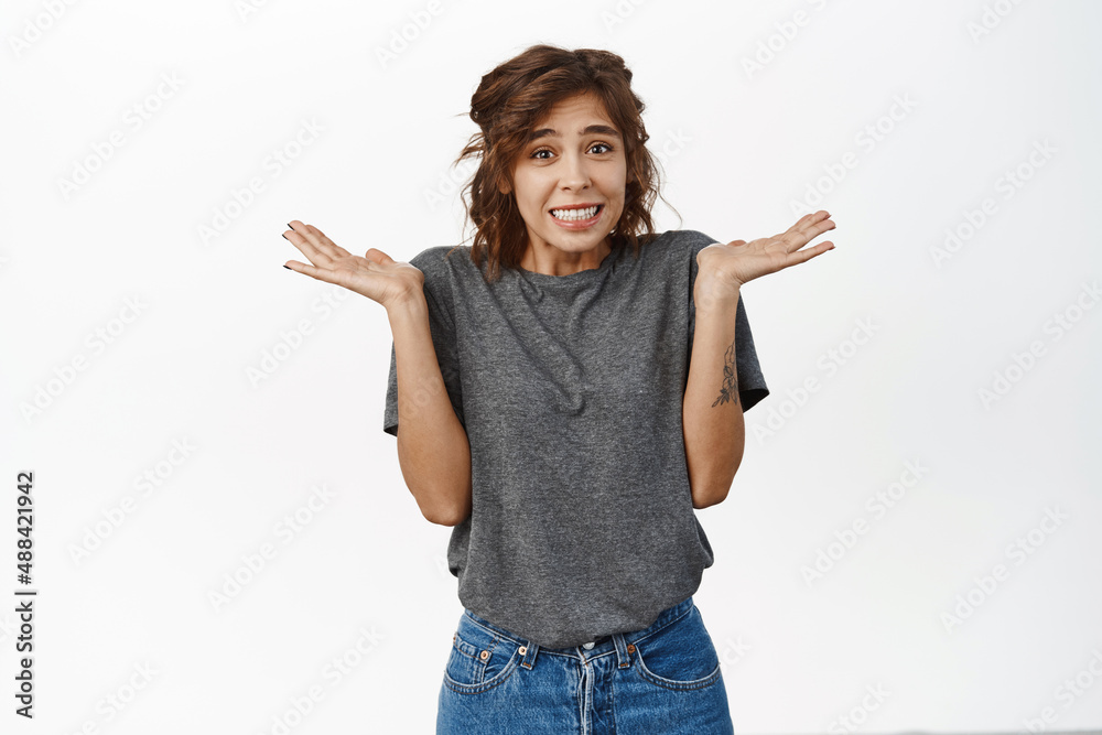 Cute smiling girl shrugging shoulders clueless and awkward, dont know ...