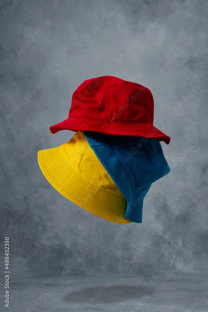 three buckets hats, red, blue, yellow, flying. Stock Photo | Adobe Stock