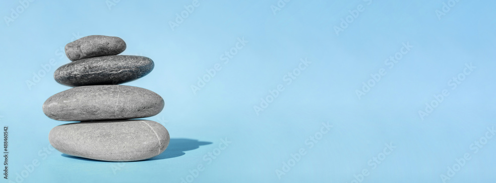 Balanced pebble stones for spa treatments on blue background. The ...