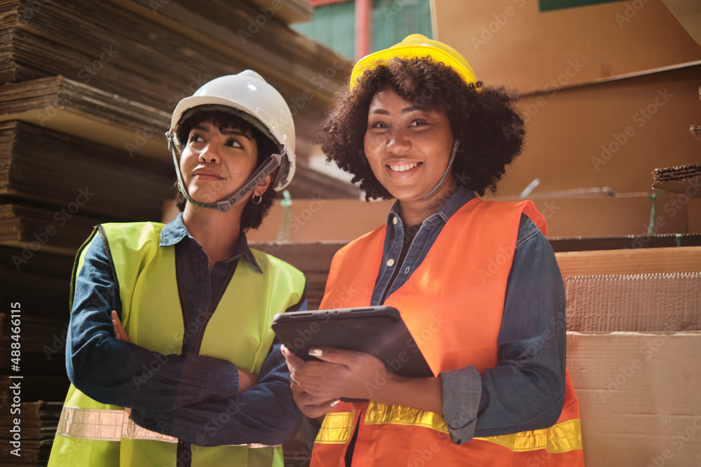 Two female workers and colleagues in safety uniforms and helmet stock ...