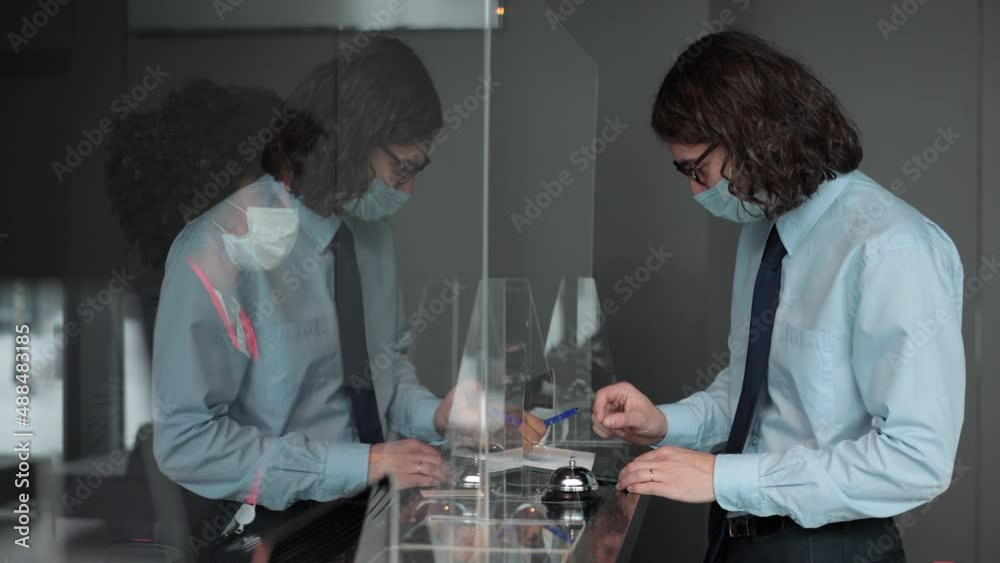 Young businessman signing paper and receiving keys on check-in table in ...