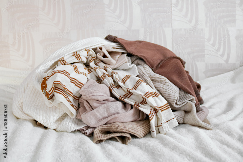 Pile of unfolded dirty clothes for laundry on the bed. Heap of used ...