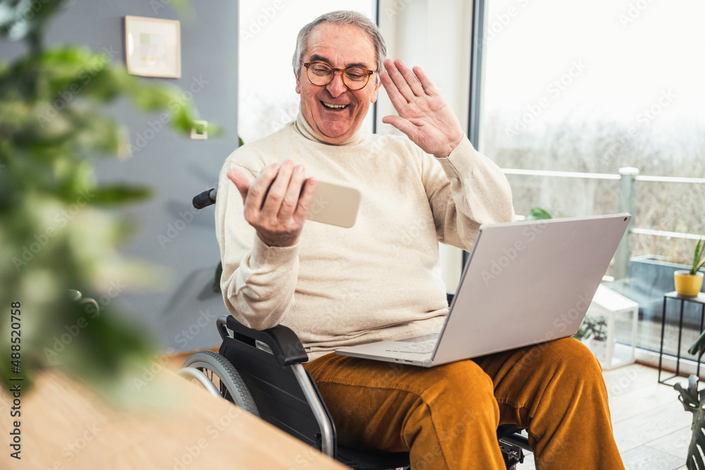 Happy disabled man waving hand on video call through smart phone at ...