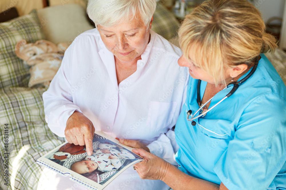 Old woman and nurse look at photo album Stock Photo | Adobe Stock