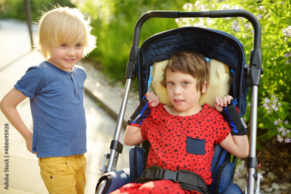 Little boy and disabled girl in wheelchair playing together in summer ...