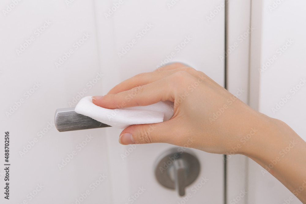 Cleaning door handles with an antiseptic wet wipe and gloves. Sanitize ...