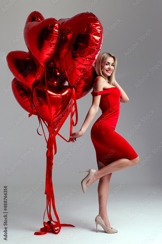 Studio portrait of a beautiful girl in a red dress with balloons in her ...
