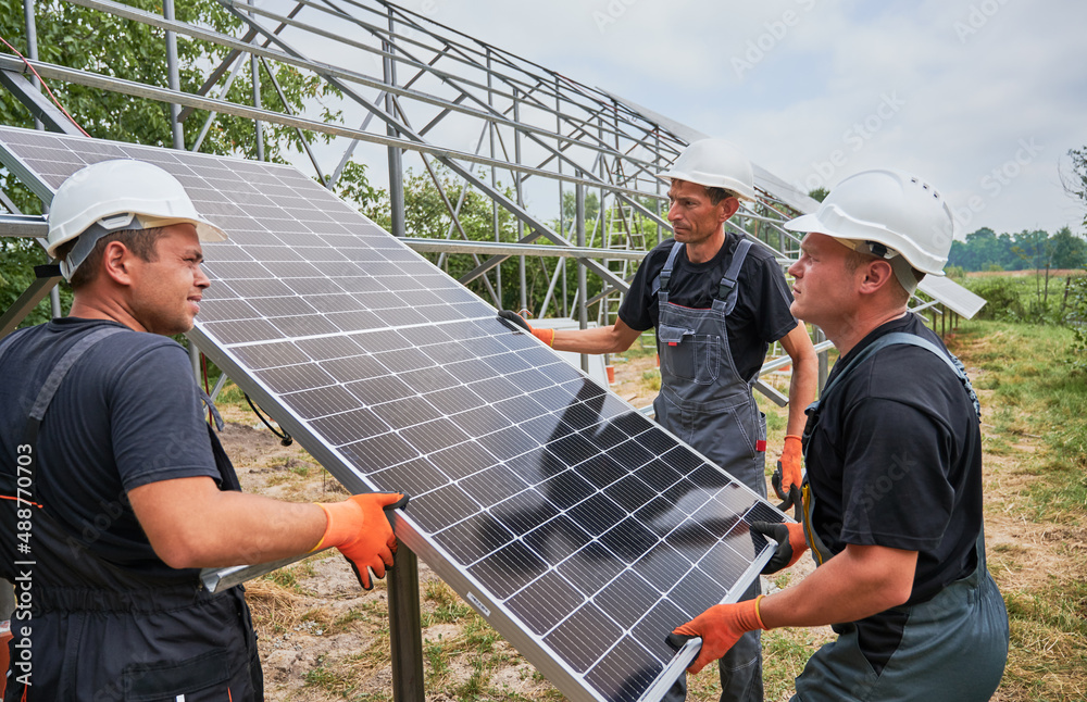Three men solar installers building photovoltaic solar panel system ...