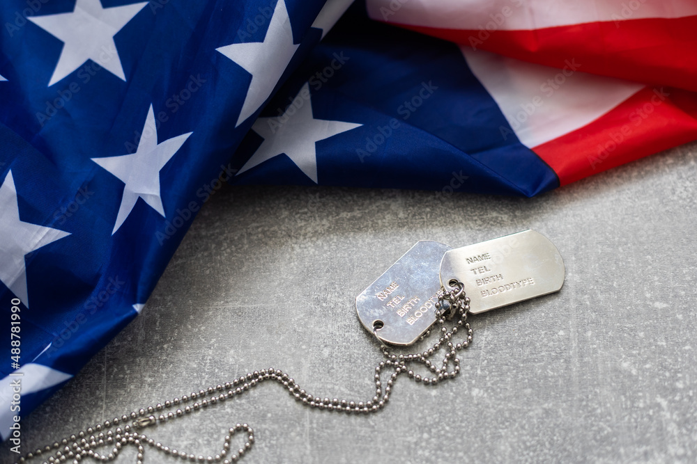 Army Dog tag token with 9mm bullets and pistol lie on folded United ...