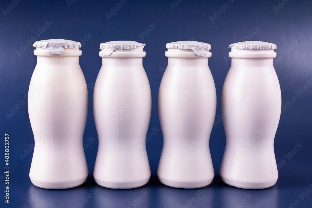 Four bottles of milk yogurt (kefir) lined up in a row close-up on a ...