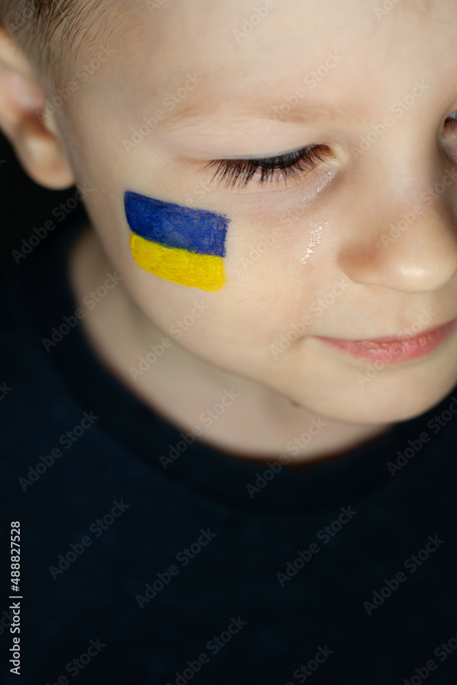 War in ukraine, a child with the flag of ukraine on his face. Pray for ...
