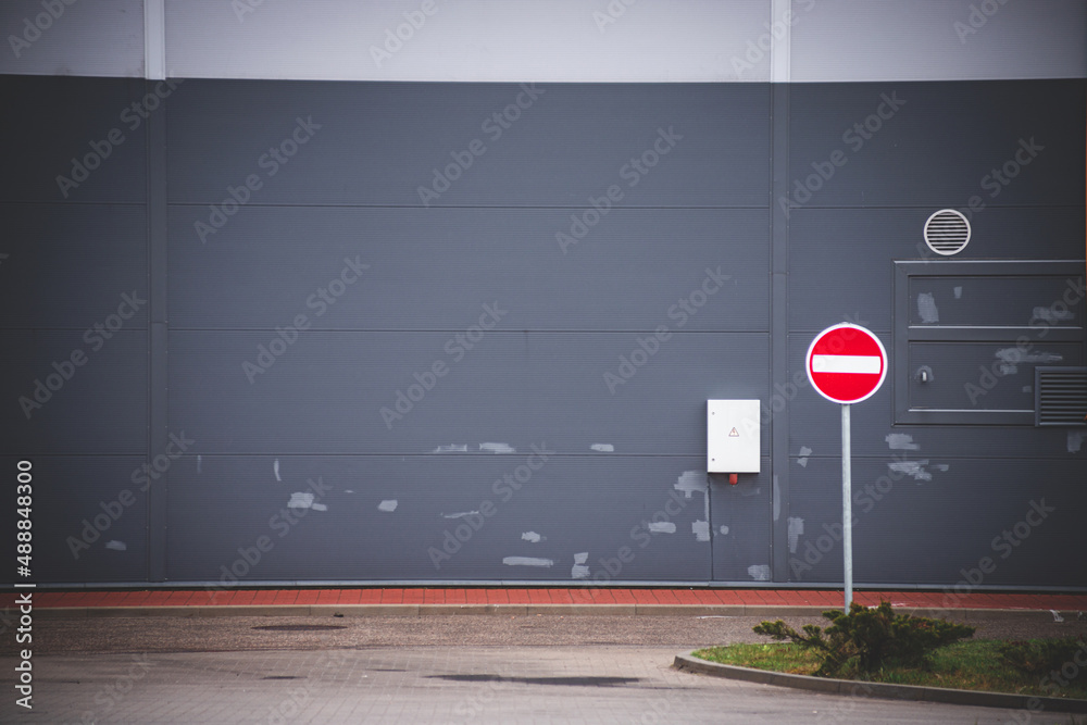 gray stripped industrial building wall, no entry road sign on green ...