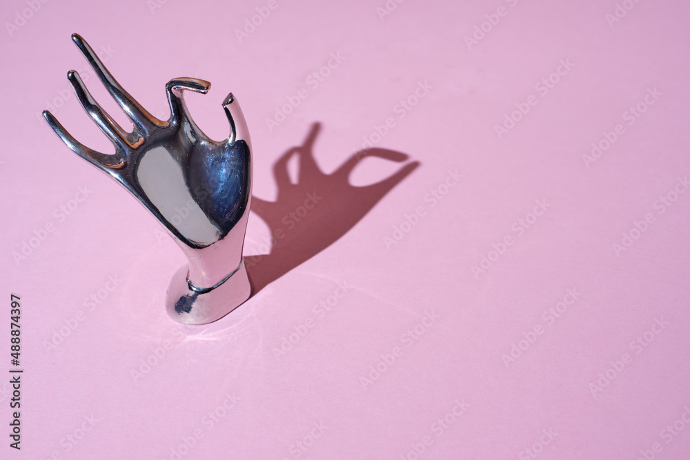 iron Hand-shaped jewelry holder with shadow on a trendy pink background ...