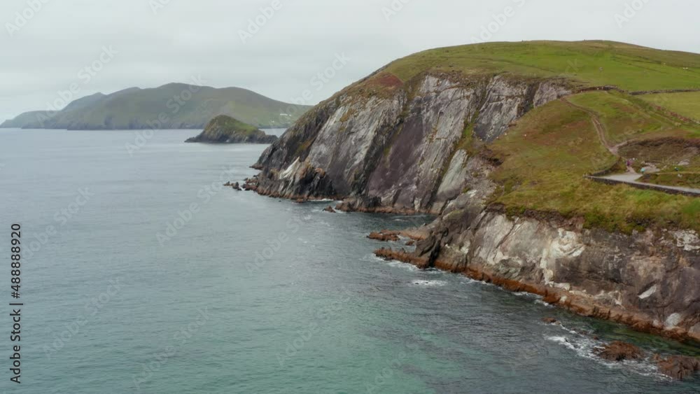 Fly along sea coast. High and steep rock slope rising from water with ...
