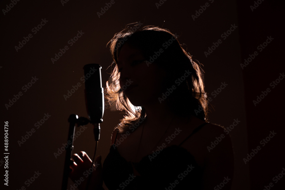 silueta de Joven cantante apasionada a contraluz Stock Photo | Adobe Stock