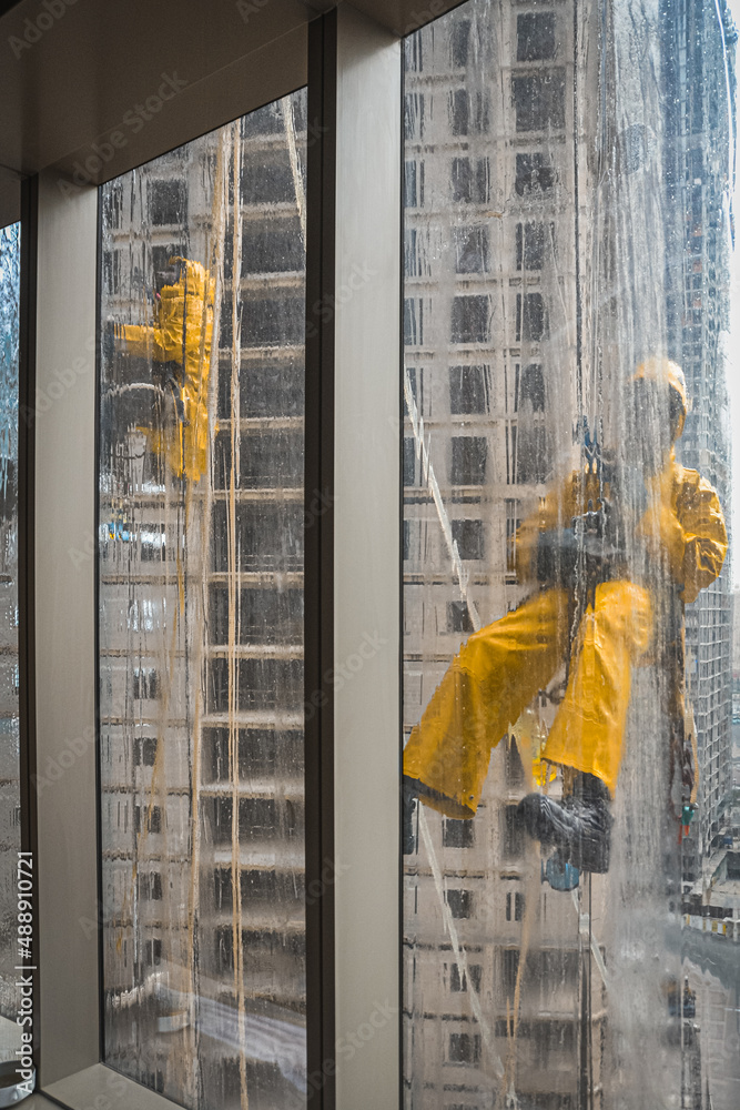 Skyscraper window cleaner hanging from a harness in Doha, Qatar. View ...