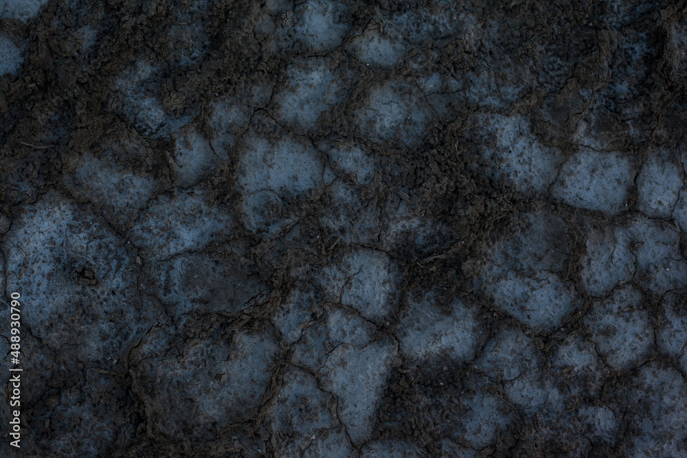 Texture of the dried earth. Dark gray background with cracks and ...
