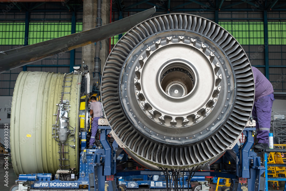 Technicians repair an aircraft gas turbine engine in the hangar. Close ...