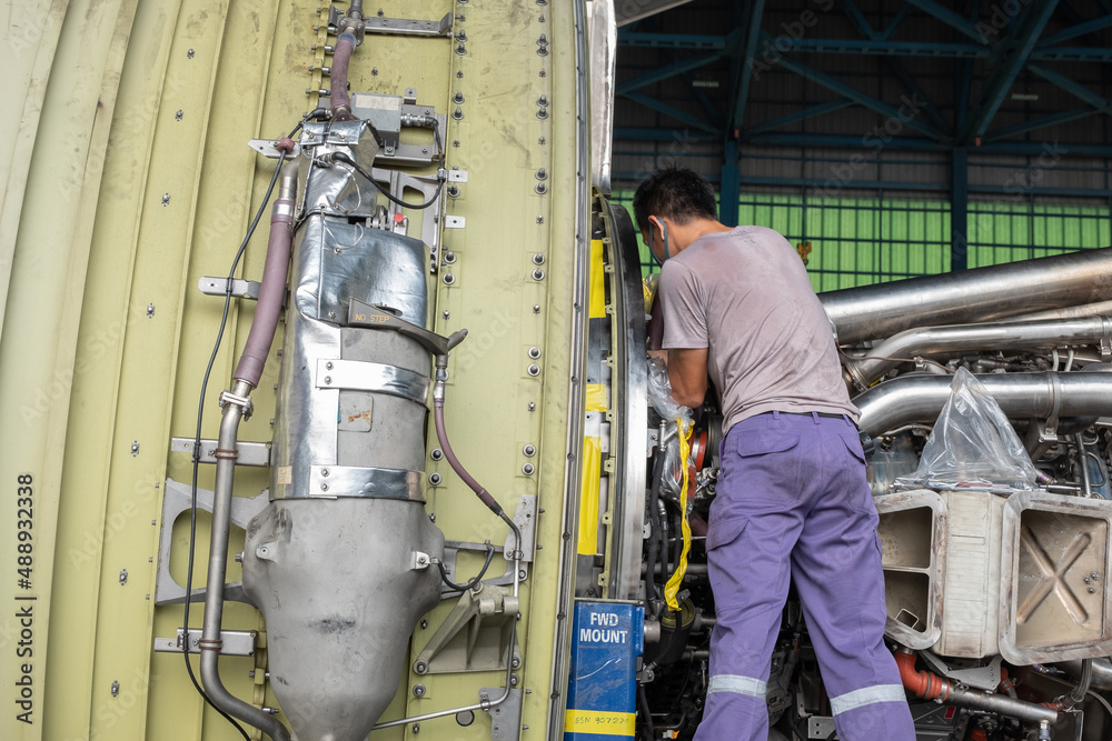 Technicians repair an aircraft gas turbine engine in the hangar. Close ...