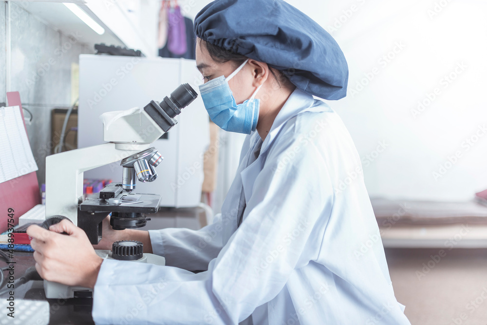An asian laboratory technician checks a swab specimen sample with an ...