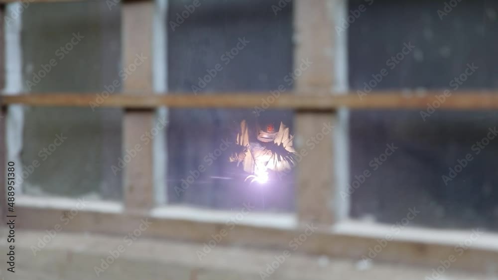 Man in suit is welding tibe in the manufacture. Picture inside window ...