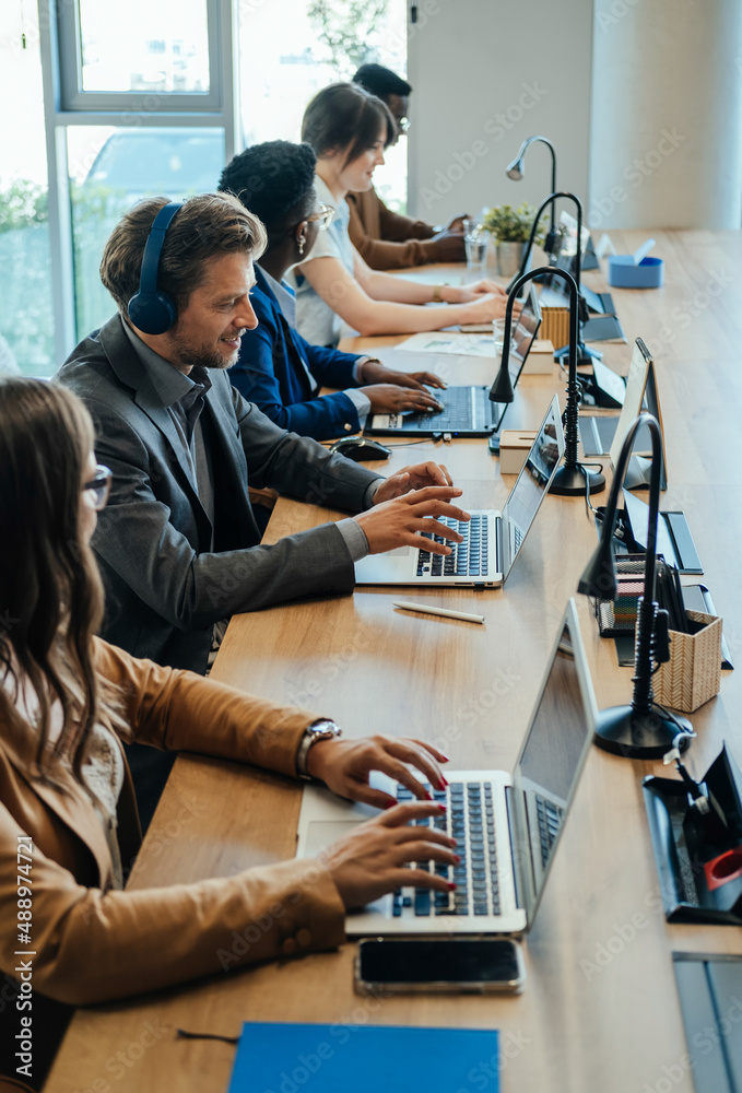 Smiling Business People Sitting in a Row and Working on Computers in ...
