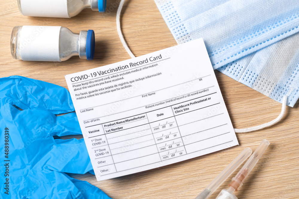 Top view of vaccination record card, syringes, and two vials of the ...