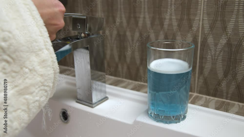 Close-up of washing a polymer aligner in a glass of cleaning solution ...