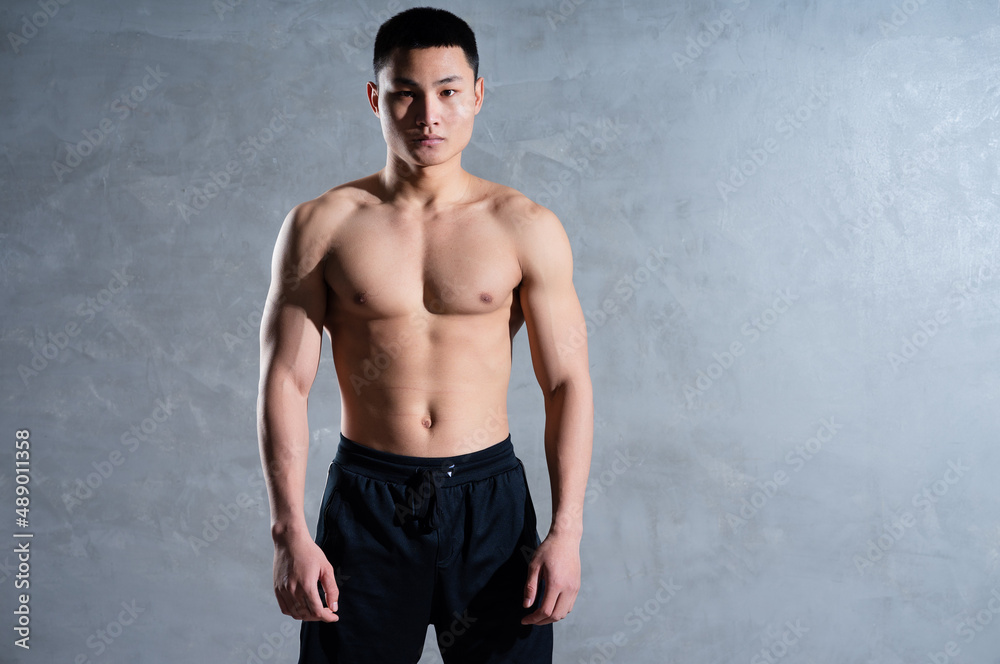 Muscular Asian man posing on gray background Stock Photo | Adobe Stock