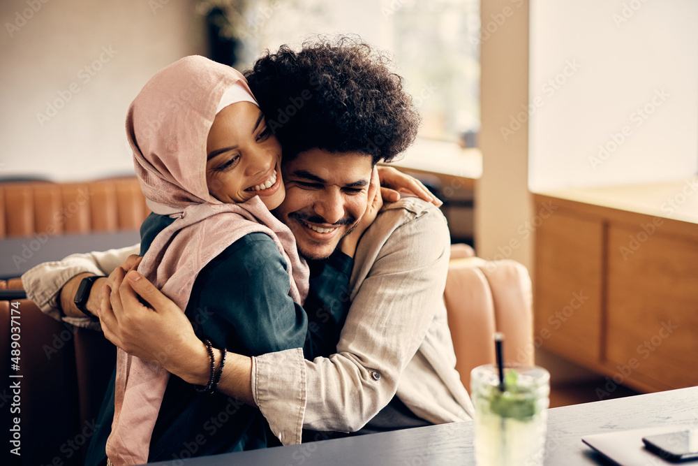 Affectionate Middle Eastern couple hugs while sitting in a cafe. Stock ...
